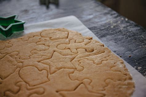 어두운 배경에 양피지 베이킹 종이에 원시 반죽에서 크리스마스 트리 스타 작은 남자 마음의 형태로 진저 브레드 쿠키를 잘라 맨 위