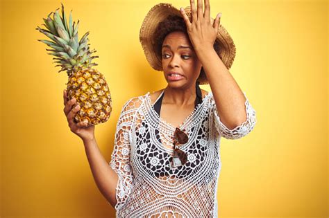 노란 고립 된 배경 위에 소나무를 들고 있는 젊은 아프리카 계 미국인 여성은 부끄러움과 깜짝 얼굴에 충격을 받고 화가 나서 좌절했습니다 실수에 대한 두려움과 화가 감정에