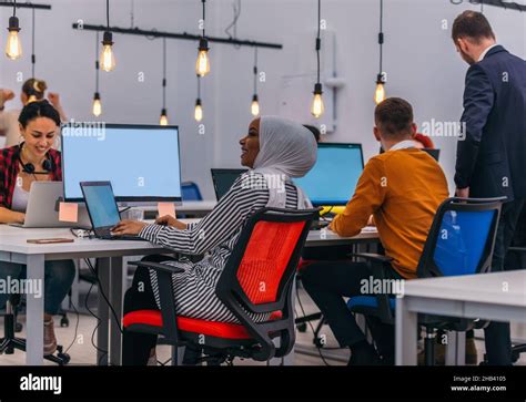 Multi Ethnic Coworkers Sitting At Desks And Working On Computers In A Modern Office Room Stock