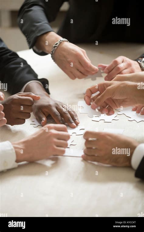 Multi Ethnic Group Of People Assembling Jigsaw Puzzle Together Hands