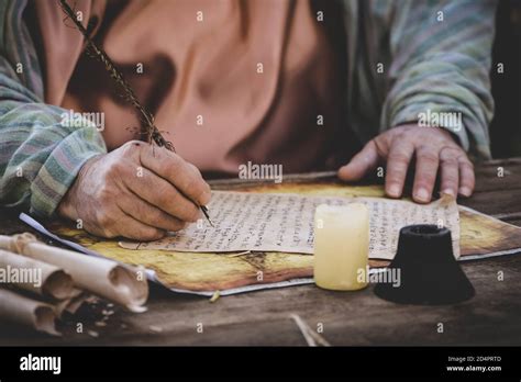 Closeup Of Man In A Robe Writing On Old Paper Scrolls Stock Photo Alamy