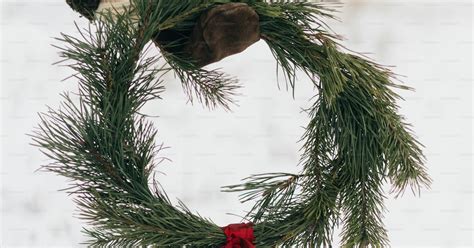 시골의 겨울 휴가 겨울 공원에서 크리스마스 화환을 가진 세련된 여자 눈 덮인 겨울 들판에서 빨간 활이 달린 크리스마스 화환을