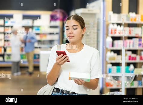 In Pharmacy Girl Visitor Scan QR Code And Reads Composition Of Cream For Problematic Skin Stock