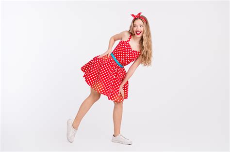 복고풍 물방울 무늬 드레스를 입은 즐거운 젊은 여성이 에너지와 매력이 넘치는 흰색 배경에 장난스럽게 포즈를 취하고 있습니다 16 17 살에 대한 스톡 사진 및 기타 이미지