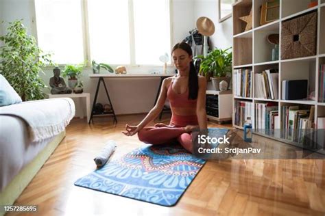 젊은 여자 와 그녀의 눈을 감고 앉아 에 A 요가 매트 에 머드라 제스처에 손가락으로 연꽃 위치 집에서 호흡 운동과 명상연습 20 29세에 대한 스톡 사진 및 기타 이미지