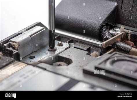 The Screwdriver Unscrews The Fastening Bolt Of The Old Dusty Processor Computer Board