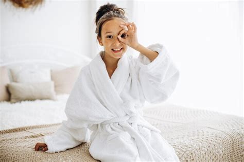 Premium Photo Cute Girl Sitting On Bed In Bathrobe