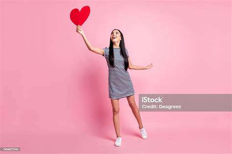 핑크 파스텔 색상 배경 위에 고립 된 재미를 가지고 날아 다니는 손 심장을 들고있는 사랑스러운 쾌활한 핏 소녀의 전체 길이 몸 크기보기 갈색 머리에 대한 스톡 사진 및 기타