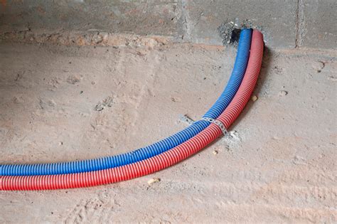 파란색과 빨간색 플라스틱 골판지 튜브가 바닥을 가로질러 뻗어 있습니다 건물의 수리 또는 건설 중에 열 및 물 공급의 임시 통신 0명에 대한 스톡 사진 및 기타 이미지