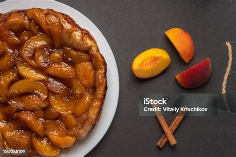 어두운 배경에 흰색 접시에 복숭아와 캐러멜타르타틴 복숭아와 계피 스틱의 조각 근처 맨 위 보기 수평 방향 복숭아류에 대한 스톡 사진 및 기타 이미지 Istock