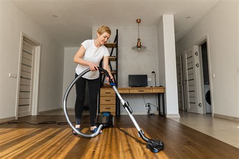 거실에서 진공 청소기로 쪽모이 세공 마루 바닥을 청소하는 성숙한 여자 호텔룸 관리 직원에 대한 스톡 사진 및 기타 이미지 호텔룸 관리 직원 중장년 가사 집안일