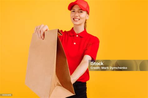빨간 유니폼을 입은 배달원이 음식과 종이 봉투를 들고 여성 직원은 택배로 일합니다 T 셔츠에 대한 스톡 사진 및 기타 이미지 T 셔츠 가방 노랑 Istock