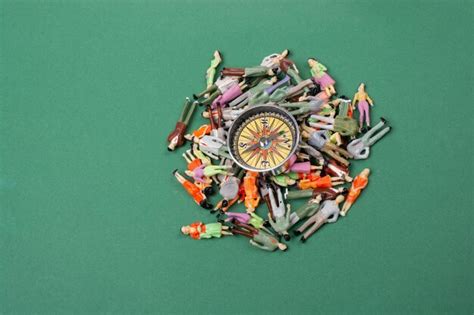Crowd Of Miniature People Figurine Around A Compass Premium Photo