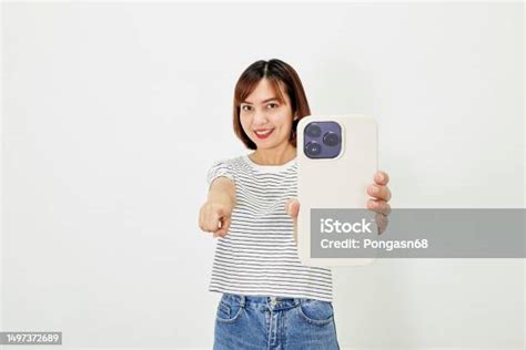 티셔츠와 청바지를 입은 젊은 아시아 여성이 하얀 배경에 스마트폰을 보여준다 20 29세에 대한 스톡 사진 및 기타 이미지 20 29세 35 39세 Brand Name