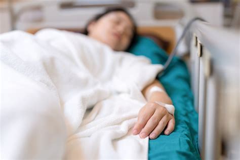 아시아 환자 여성은 병원 병동에서 손에 식염수와 주사기 라인으로 침대에 누워 있습니다 손을 들어 침대 가장자리의 레일을 잡으십시오 의료 및 의료 개념 병원에 대한 스톡 사진