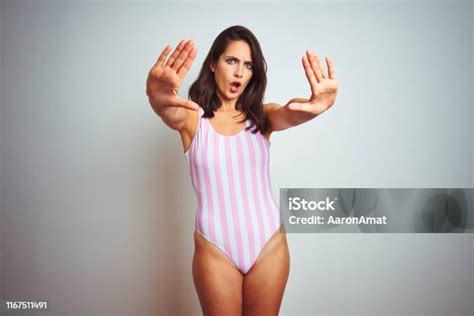 젊은 아름다운 여자 를 입고 줄무늬 핑크 수영복 수영복 위에 고립 된 배경을하고 중지 제스처 와 손 손바닥 화가 와 좌절 표정 갈색 머리에 대한 스톡 사진 및 기타 이미지