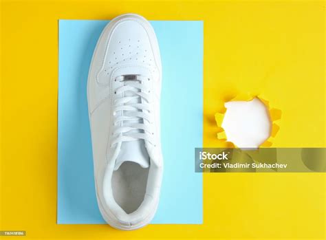 복사 공간을 위한 찢어진 구멍이 있는 노란색 종이 배경의 흰색 운동화 맨 위 보기 미니멀리즘 패션 컨셉 0명에 대한 스톡 사진 및 기타 이미지 Istock