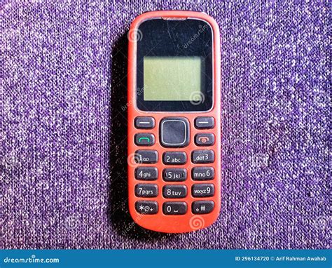 Old Mobile Phone With Texting Or Sms Button Keyboard Or Keypad On Sparkling Purple Fabric Old Mobile Phone With Texting Or Sms Button Keyboard Or Keypad On Sparkling Purple Fabric