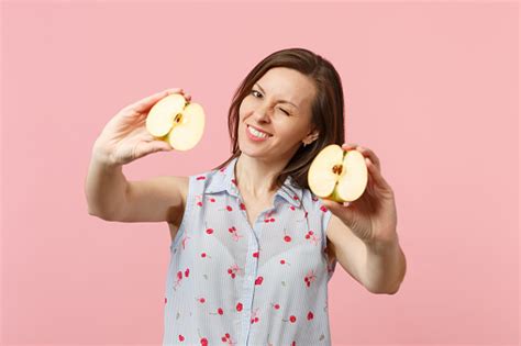 명랑 깜박임 분홍색 파스텔 배경에 고립 된 신선한 잘 익은 사과 과일의 Halfs 손에 들고 여름 옷에 젊은 여자 사람들은 생생한 라이프 스타일 휴식 휴가 개념입니다 복사