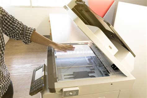Man Making Photocopy With Sheet Of Paper On Photocopier With Access Control Panel Stock Image