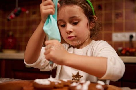 Adorable Daughter At A Kitchen Table Decorating Gingerbread Cookies