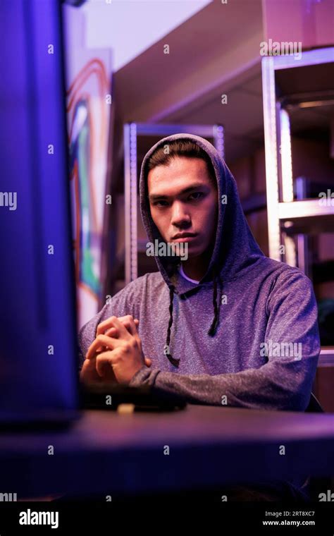Serious Hacker Developing Malicious Software And Looking At Camera Young Asian Criminal In Hood