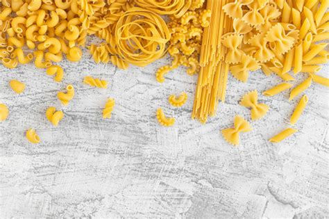 이탈리아 음식 컨셉과 메뉴 디자인 파스타 파팔레 파스타 A 리소 오레키엣 푸글리시 그노코 사르도 파팔레의 다양한 종류의 플랫 레이가 있는 하얀 돌 배경에 있습니다 0명에