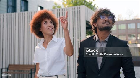 도시를 걷는 두 명의 다양한 다인종 사업가가 부동산 건물에 대해 이야기하고 걷기 협력 팀워크를 이야기하는 아프리카계 미국인 여성과 인도계 아라비아 남성이 동료에게