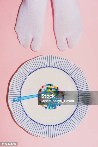 하얀 버선 양말을 신은 발은 분홍색 배경에 접시에 음식 형태의 구슬이 달린 색깔의 목걸이 근처에 서 있다 창조적 인 개념 평평한 위치 평면도 Tabi Sock에 대한 스톡