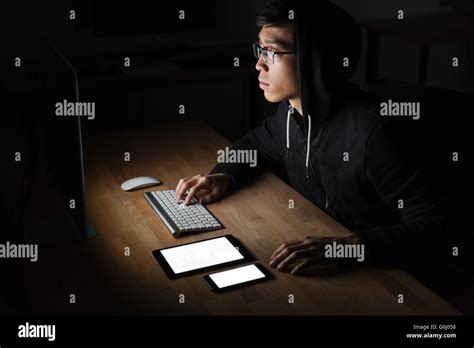 Hooded Computer Hacker Stealing Information Using Blank Screen Tablet