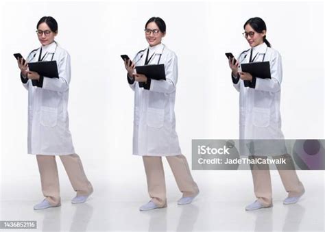 청진기를 든 전체 길이 30대 40대 아시아 여성 의사 왼쪽 오른쪽으로 앞으로 걷고 공식적인 코트 바지 신발을 신습니다 미소 병원 여성 캐리 환자 차트 전화 흰색 배경 위에