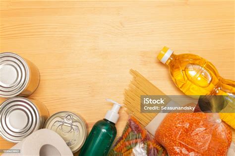 음식 배달 서비스 격리 하는 동안 온라인으로 제품을 구입 합니다 나무 배경에 건강한 음식과 방부제 해바라기 기름 토마토 파스타 빵 렌즈콩 통조림 식품 화장지 소독제 가방에