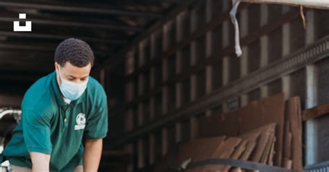 검은 티셔츠와 녹색 바지를 입은 남자가 흰색 플라스틱 의자에 앉아 있다 사진 Unsplash의 무료 기술 이미지