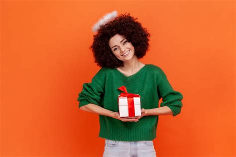 녹색 캐주얼 스타일 스웨터와 머리에 민첩을 입고 아프로 헤어 스타일을 가진 귀여운 매력적인 천사 의 여성은 축하 선물 상자를 들고 20 24세에 대한 스톡 사진 및 기타