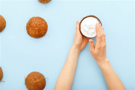 코코넛 유기농 화장품 코코넛 크림 오일 파스텔 블루 컬러 배경에 여성의 손에 피부 또는 머리에 대한 로션 부드러운 피부를 위한 스킨 케어 보습 크림 건강과 뷰티 컨셉
