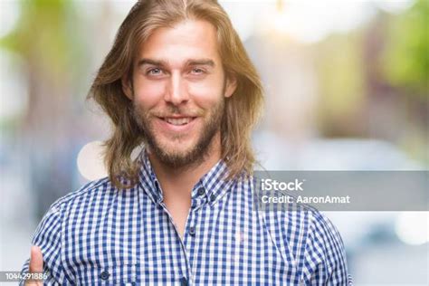 행복 한 엄지손가락 손으로 제스처를 하 고 격리 된 배경 위에 긴 머리를 가진 젊은 잘생긴 남자 승인 성공을 보여주는 카메라를 보고 하는 식 긍정적인 감정 표현에 대한 스톡