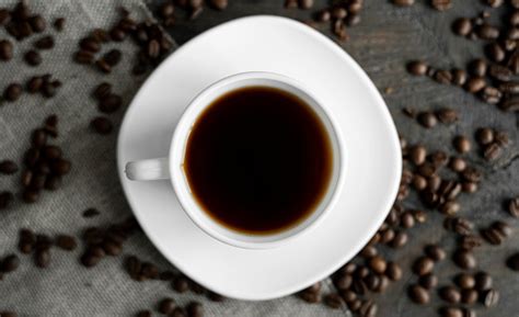 나무 테이블 배경에 구운 커피 콩커피 컵 나무 테이블에 흩어져 있는 커피 콩이 있는 검은 색 코프 잔 신선한 커피 콩 갈색에 대한 스톡 사진 및 기타 이미지 Istock