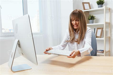 irritated blonde businesswoman screaming to keyboard raging after