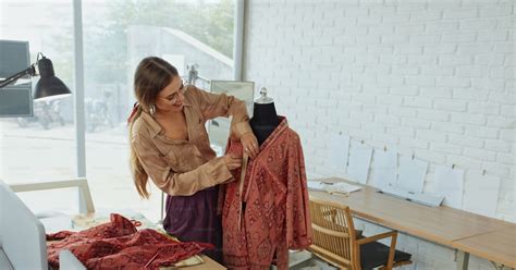 직업 워크샵에서 패션 디자이너 아름다운 여성 재단사는 마네킹에 드레스를 측정하고 스케치북에서 무언가를 기록합니다 성공 자영업자 자신의 의류 아틀리에에서 일하는 여성