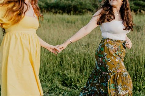 Closeup Shot Of A Same Sex Lesbian Couple Walking Holding Hands On A Grass Field In Daylight