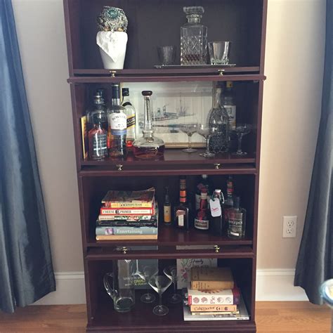 A Book Shelf Filled With Lots Of Books Next To A Vase And Glasses On Top Of It