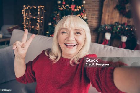 그녀의 자화상 그녀 좋은 매력적인 사랑스러운 쾌활한 쾌활한 쾌활한 회색 머리 할머니 지출 겨울 12 월 휴가 장식 된 산업 로프트 스타일의 인테리어 하우스에서 V 사인을