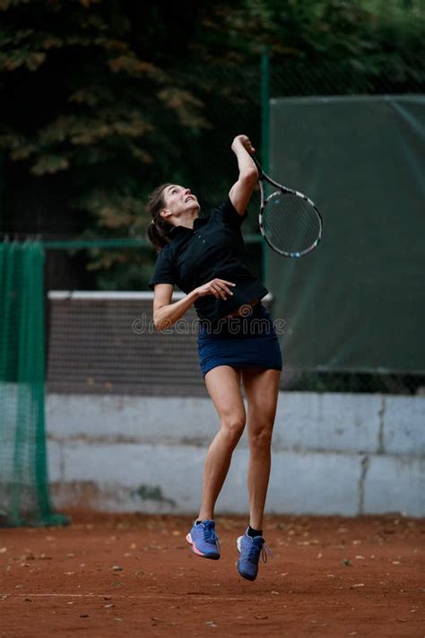 Front View Of Active Bouncing Female Tennis Player With Tennis Racket In Her Hand Behind Her