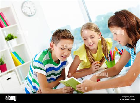 Group Of Curious Classmates Looking At Note In Notebook In Girl Hands