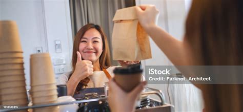 가게에서 고객에게 종이 봉투에 테이크 아웃 음식을 제공하면서 엄지 손가락을 만들고 엄지 손가락을 보여주는 웨이트리스 20 24