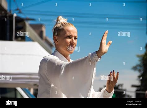 A Serene Tai Chi Master In A Flowing White Suit Gracefully Performs On A Bustling Street Her