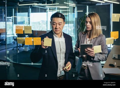 Two Employees Writing A Plan And Tasks On The Task Board An Asian Man