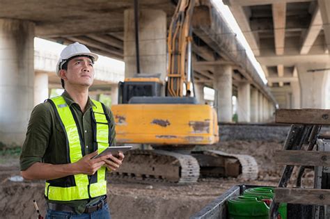 기술자는 배경에 백 호와 함께 건설 현장에서 일하고 있습니다 30 34세에 대한 스톡 사진 및 기타 이미지 30 34세 개발 건설 기계류 Istock