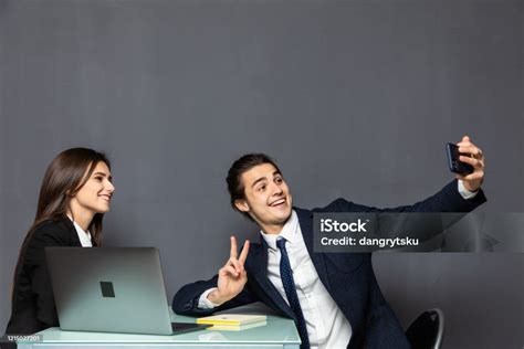 회색 배경 위에 고립 된 셀카를 찍는 양복을 입고 책상에 앉아있는 행복한 젊은 비즈니스 커플의 초상화 기업 비즈니스에 대한 스톡 사진 및 기타 이미지 Istock