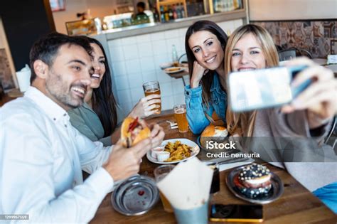 식당에서 햄버거를 먹으면서 스마트 폰으로 셀카를 찍는 친구의 행복한 그룹 4 명에 대한 스톡 사진 및 기타 이미지 4 명 건강에 좋지 않은 음식 공유 개념 Istock